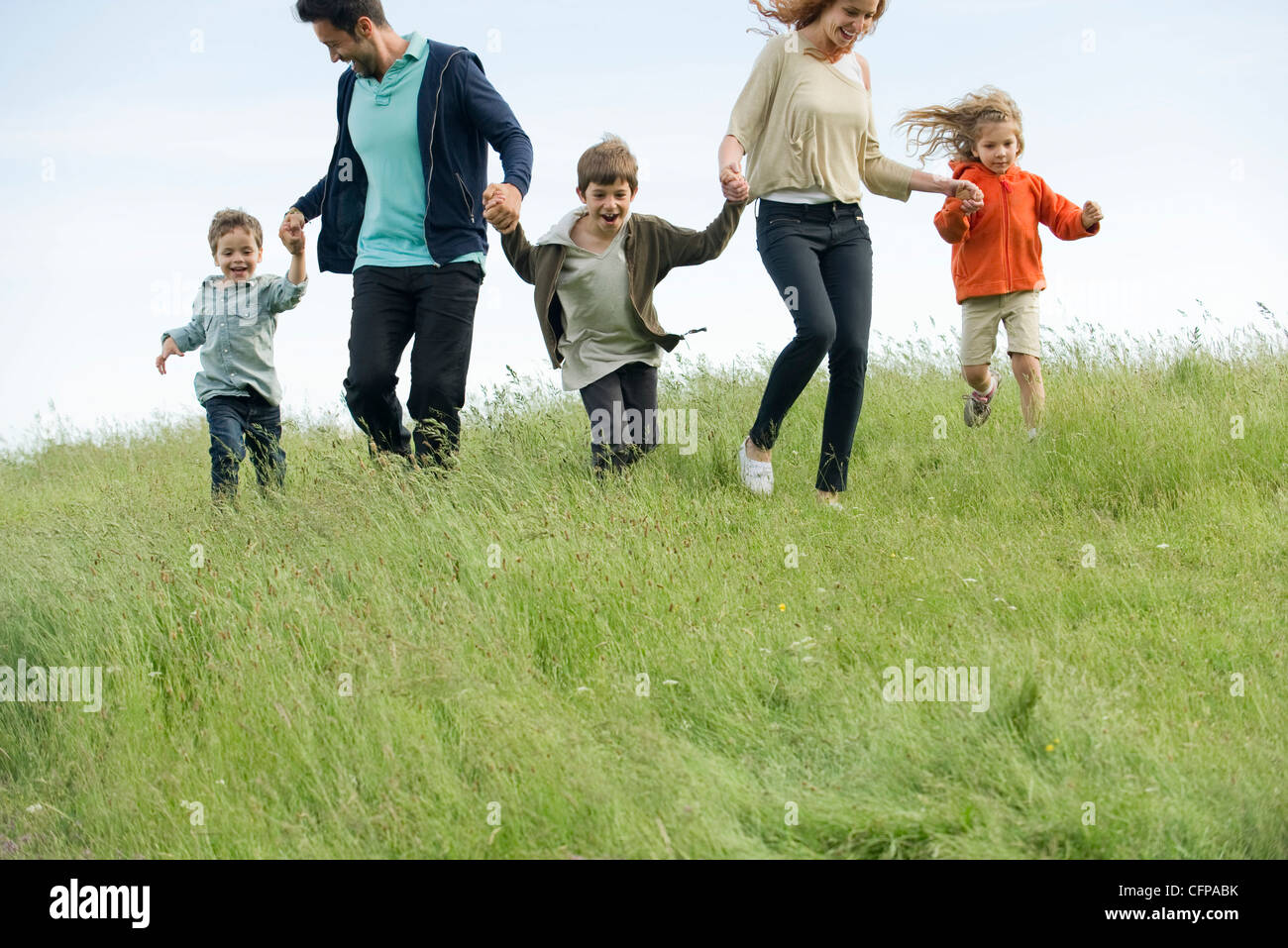 Family running hand in hand in field Stock Photo - Alamy