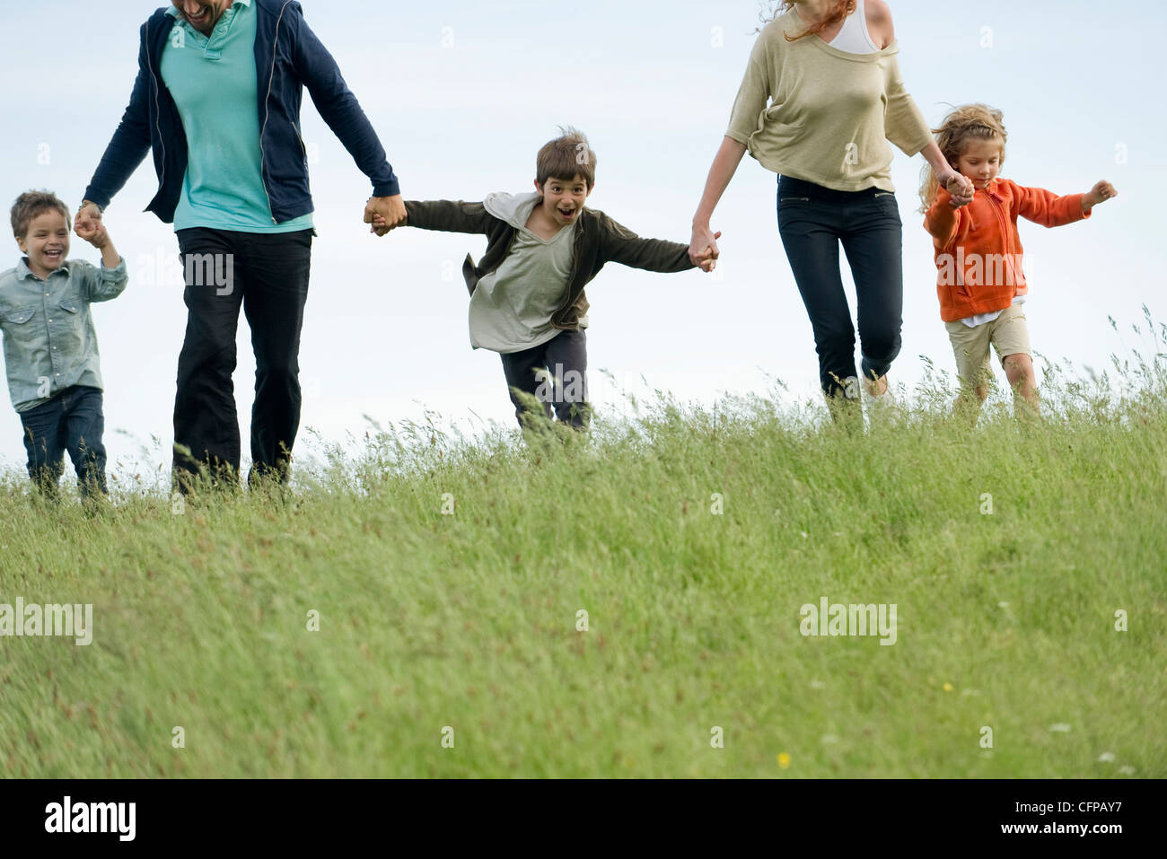 Family running together hand in hand in field Stock Photo - Alamy