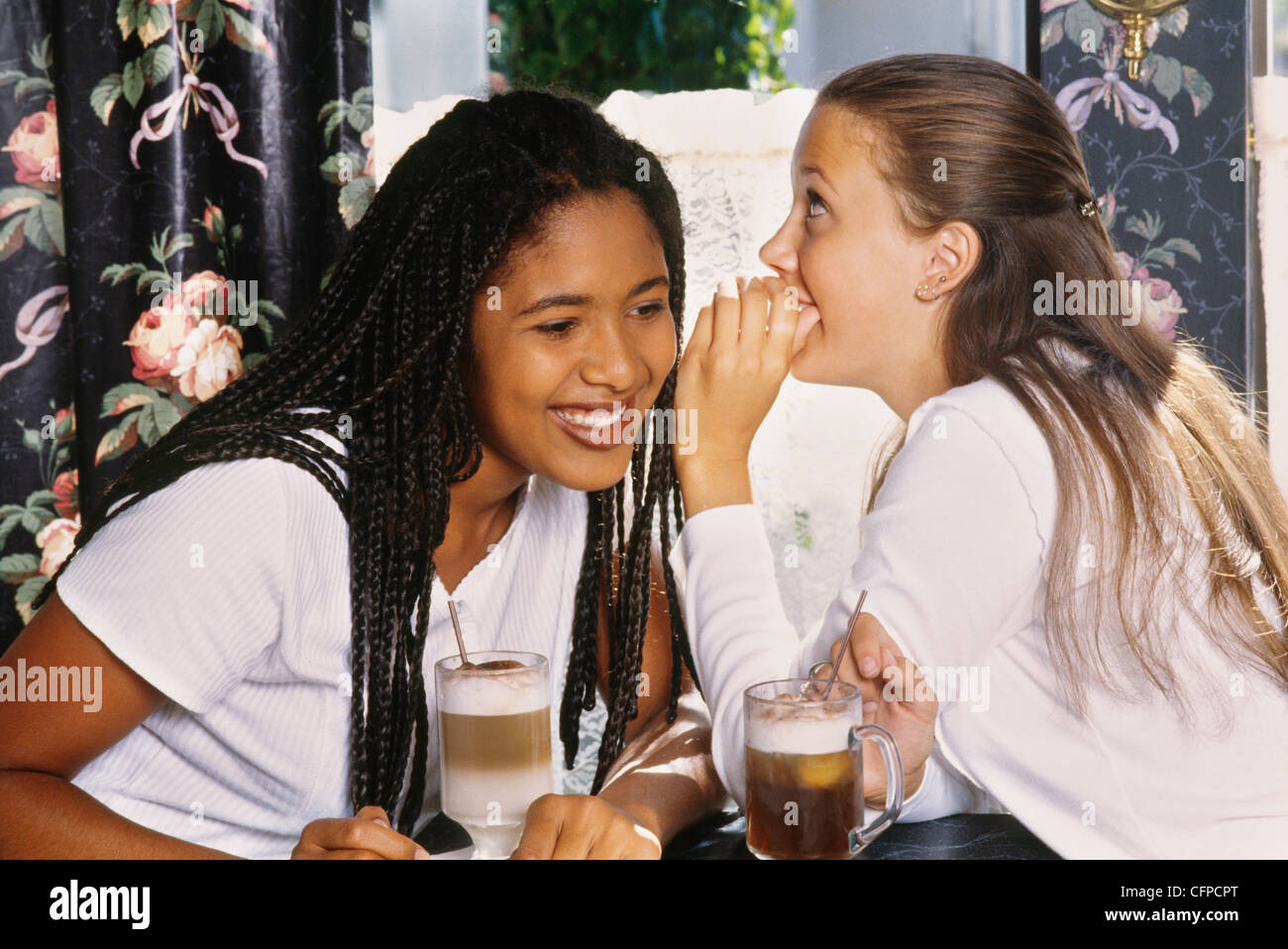Two smiling girls sharing secrets hi-res stock photography and images ...