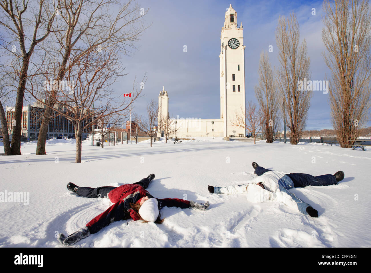 Girls Making Snow Angels with Clock Tower in Background Stock Photo - Alamy