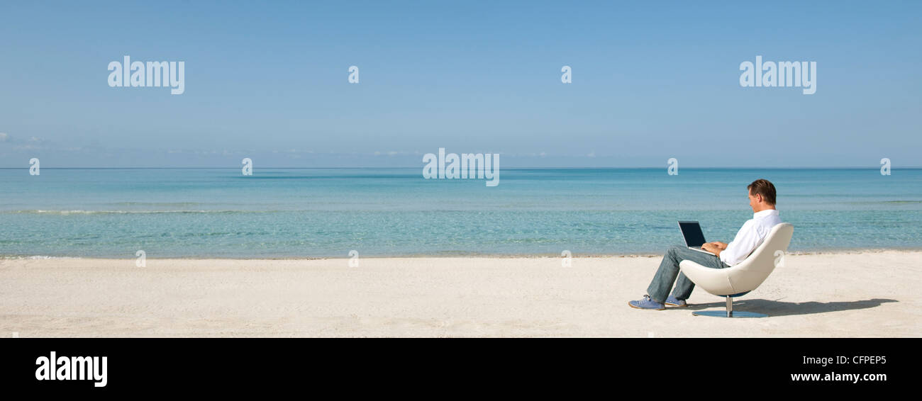 Man using laptop computer at the beach Stock Photo - Alamy