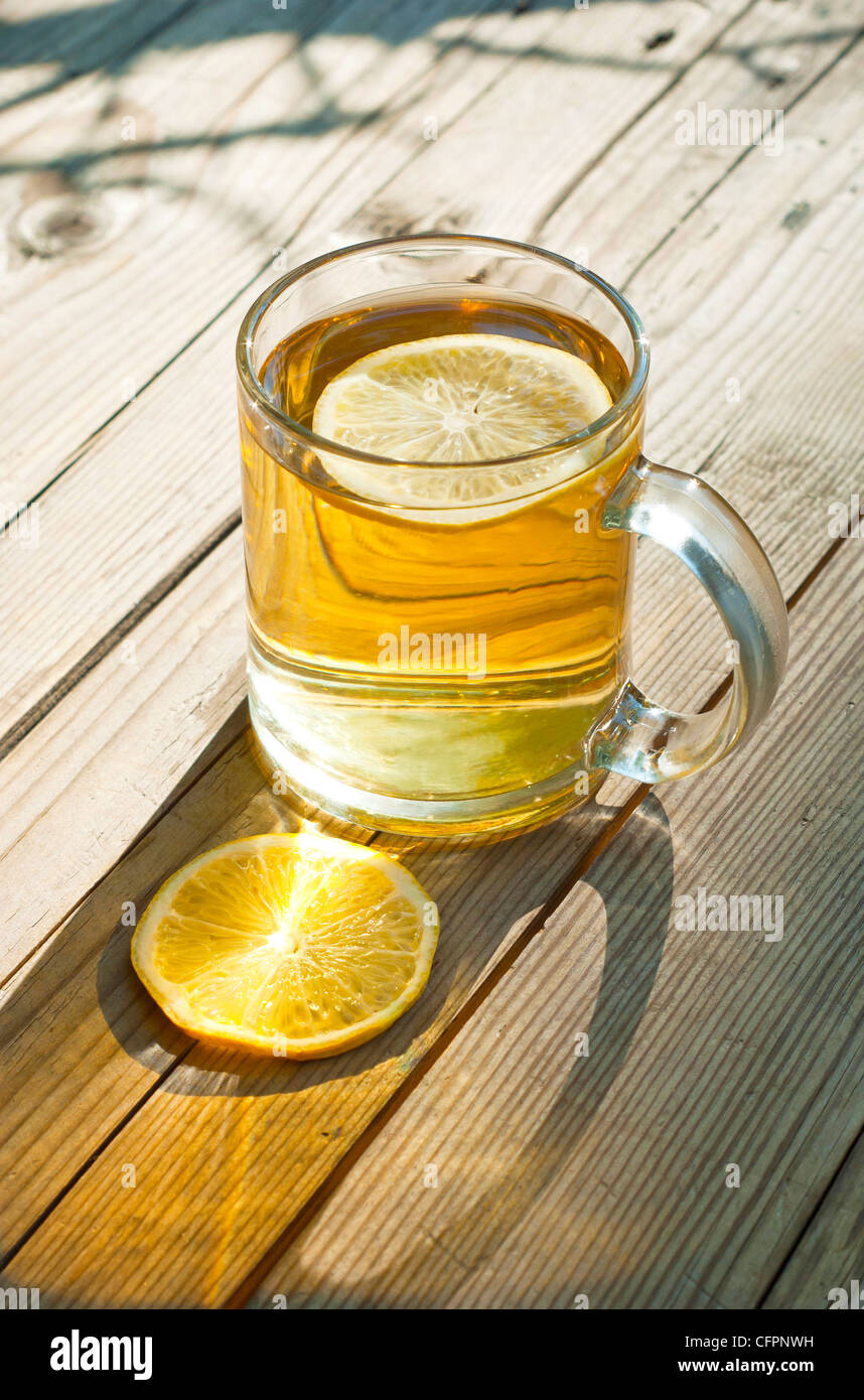 tea in glass cup and sliced lemon, wooden table Stock Photo - Alamy