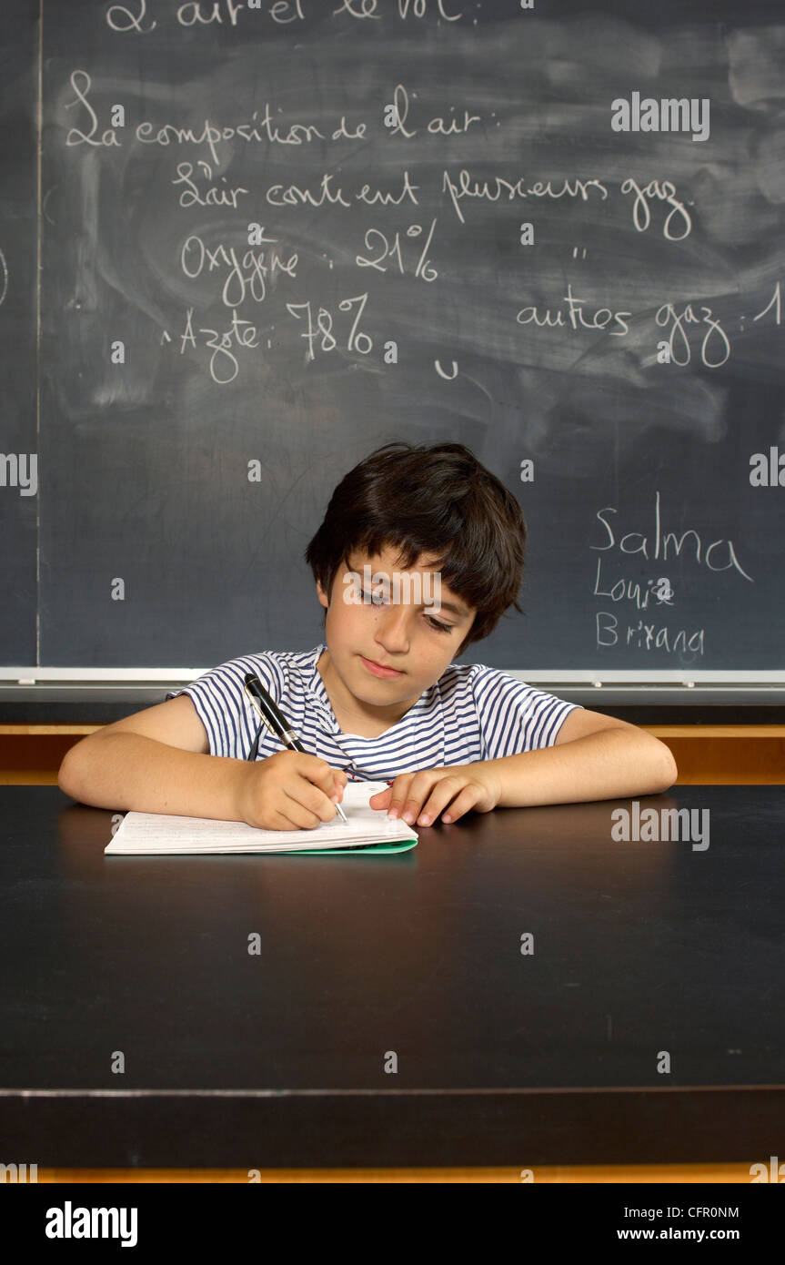 Boy Writing at Desk in Classroom Stock Photo - Alamy