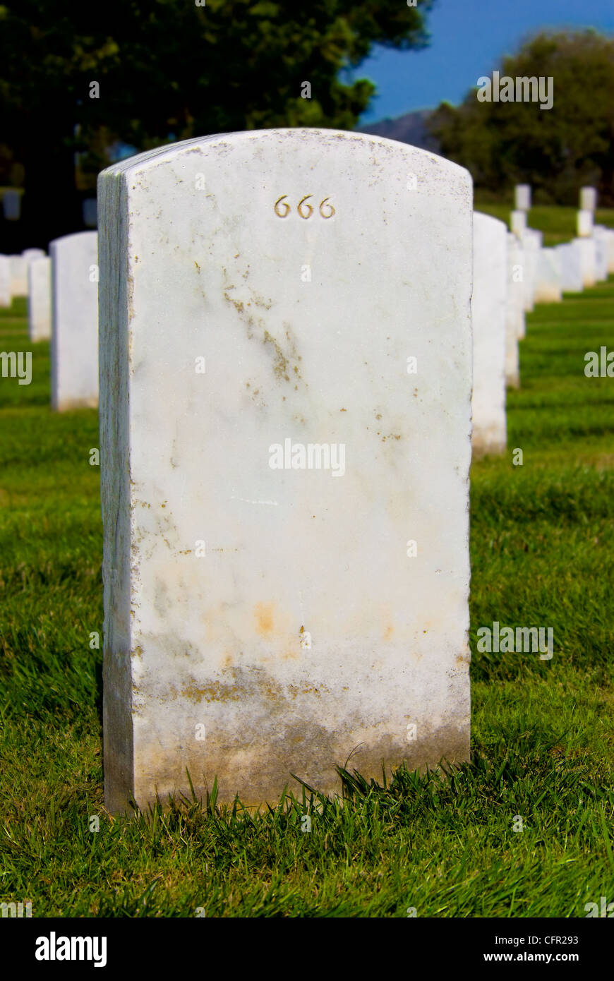 Headstone in a graveyard with evil 666 engraving with clipping path ...