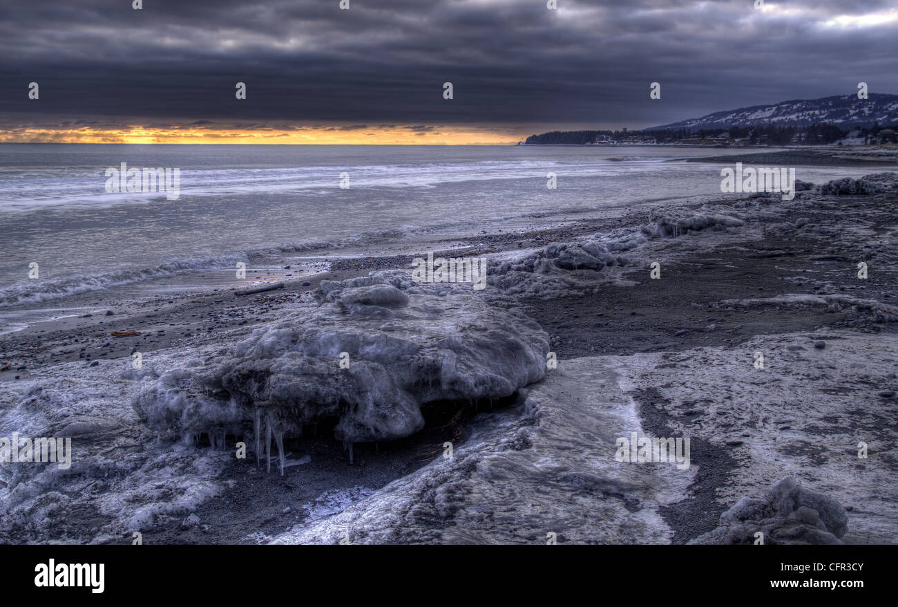Cold beach near Homer Alaska with ice chunks at sunset with dark storm ...