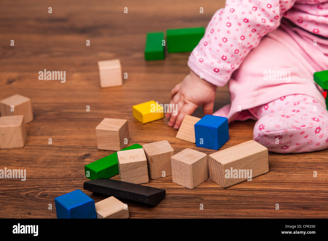 Infant child playing with bricks on wooden floor Stock Photo - Alamy
