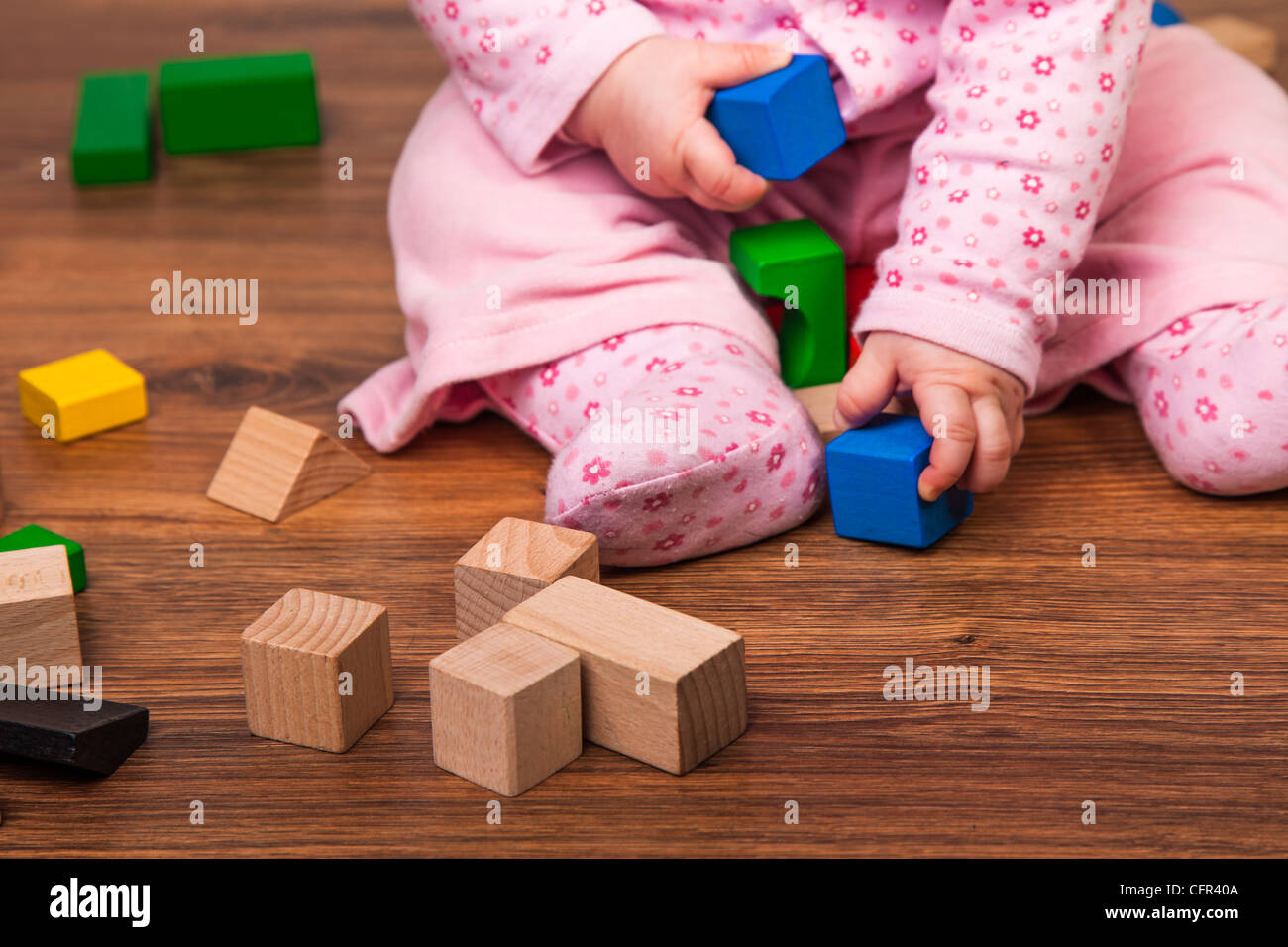 Infant child playing with bricks on wooden floor Stock Photo - Alamy