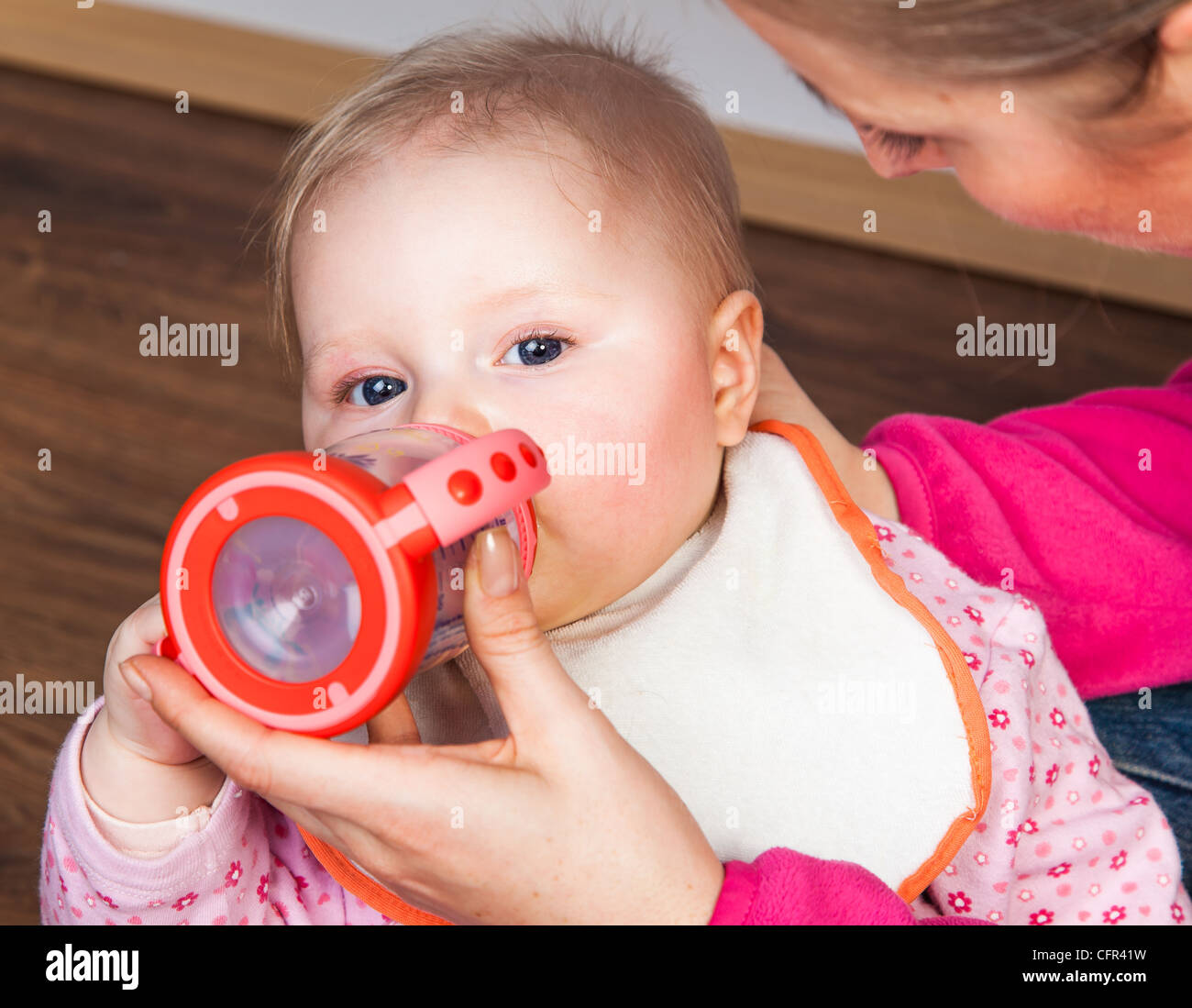 Mother giving infant daughter bottle with tea Stock Photo - Alamy