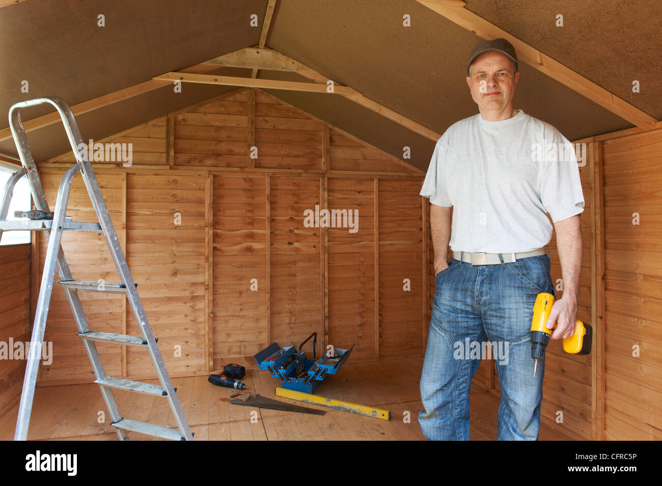 Portrait of builder standing by ladder with tools in background Stock ...