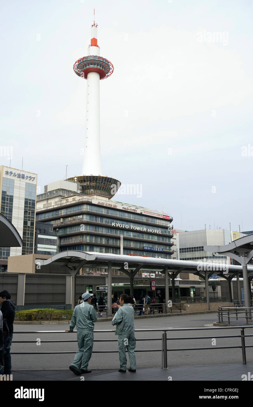 two Japanese workers standing at fence in front of Kyoto tower, Kyoto ...