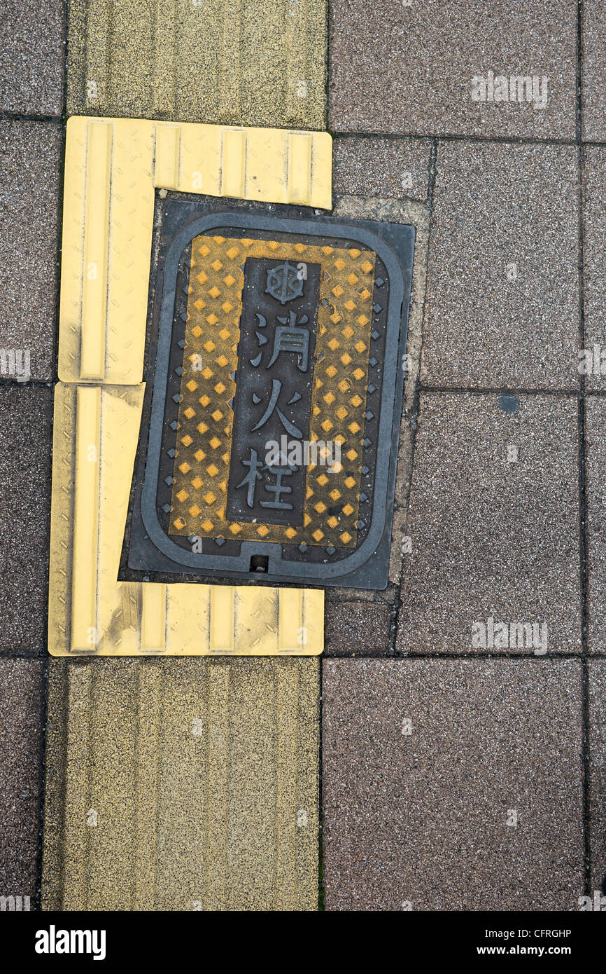 yellow mark and lid with Japanese Kanji letters in the pavement, Japan ...