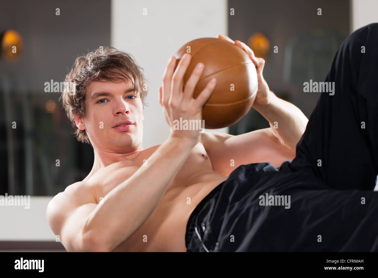 Young man is exercising with medicine ball in gym to strengthen his ...