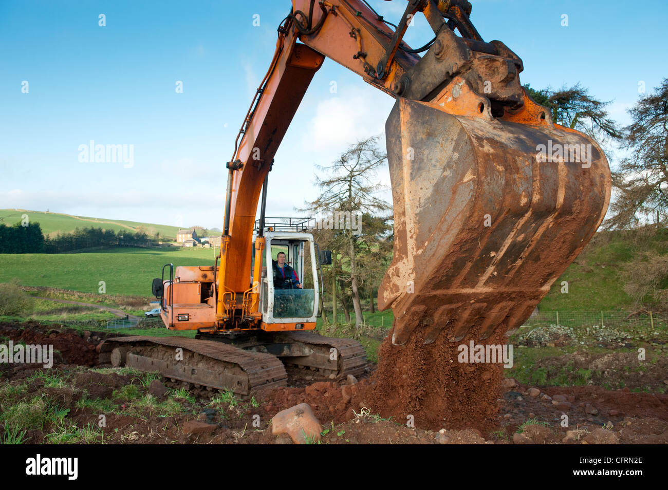 Big excavator digging stone on a hillside Stock Photo - Alamy