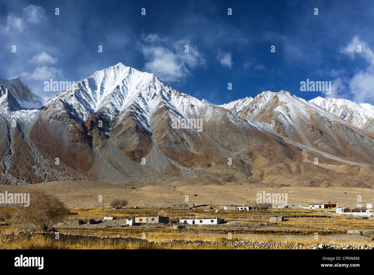 Maan village under a crisp blue sky and the snow capped peaks of the ...