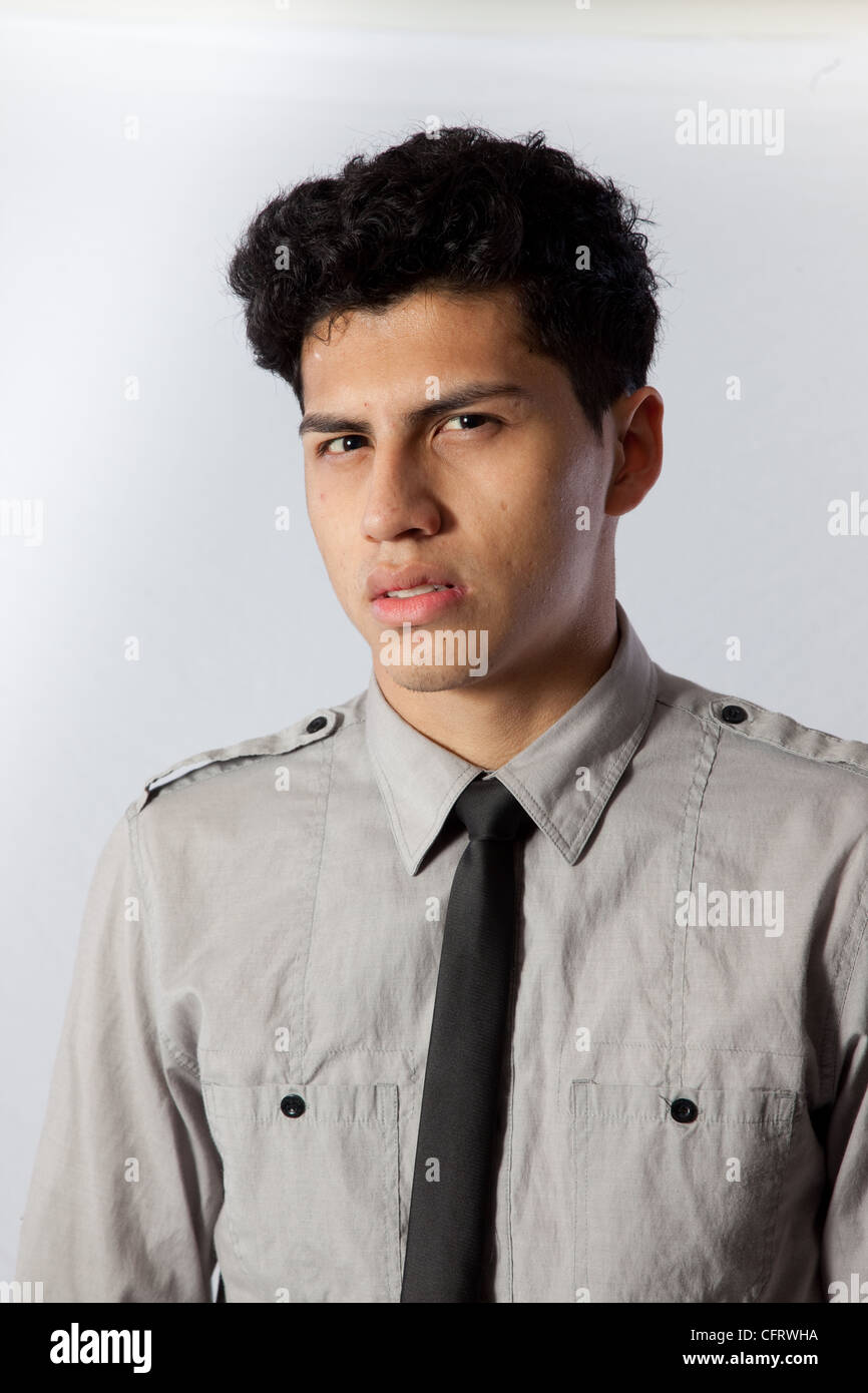 Handsome young Hispanic man in a shirt and dark tie, looking at the ...