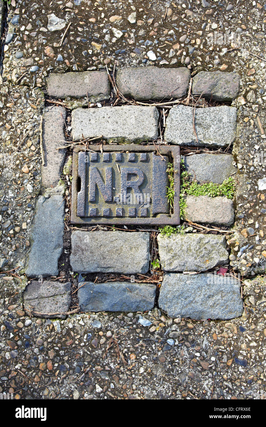 Small inspection cover surrounded by pebbles and tarmac Stock Photo - Alamy