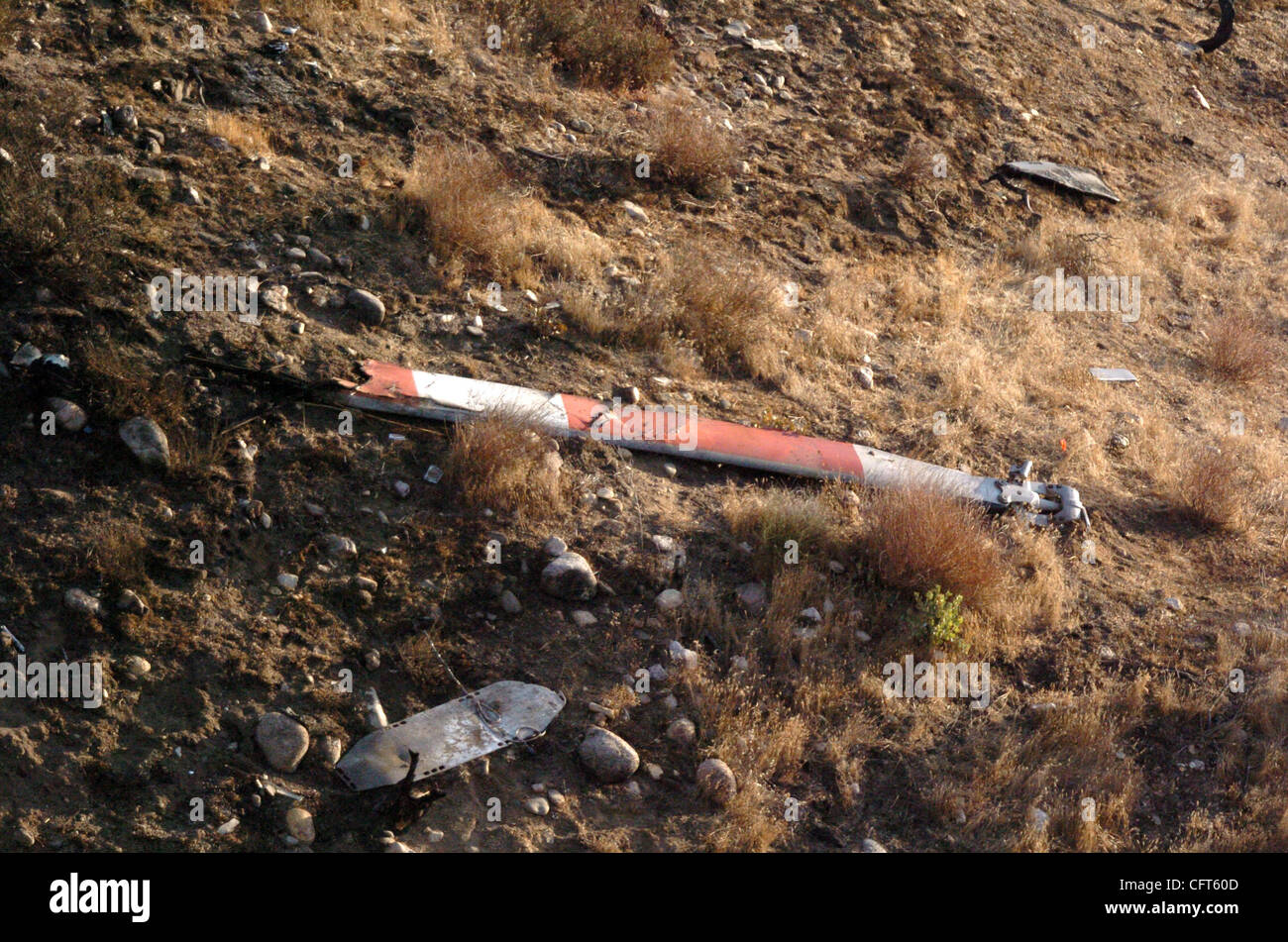 A snapped helicopter rotor blade rests inside a large debris field ...