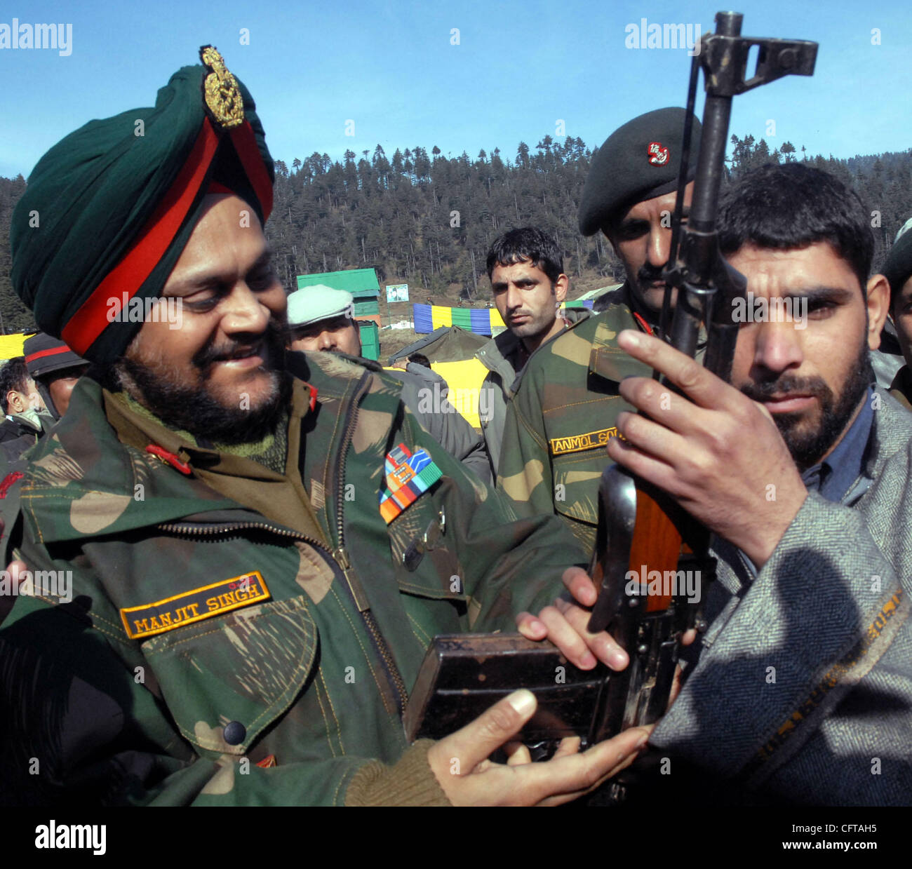 Kashmiri Muslim militant (R) hands over a rifle to an Indian army ...
