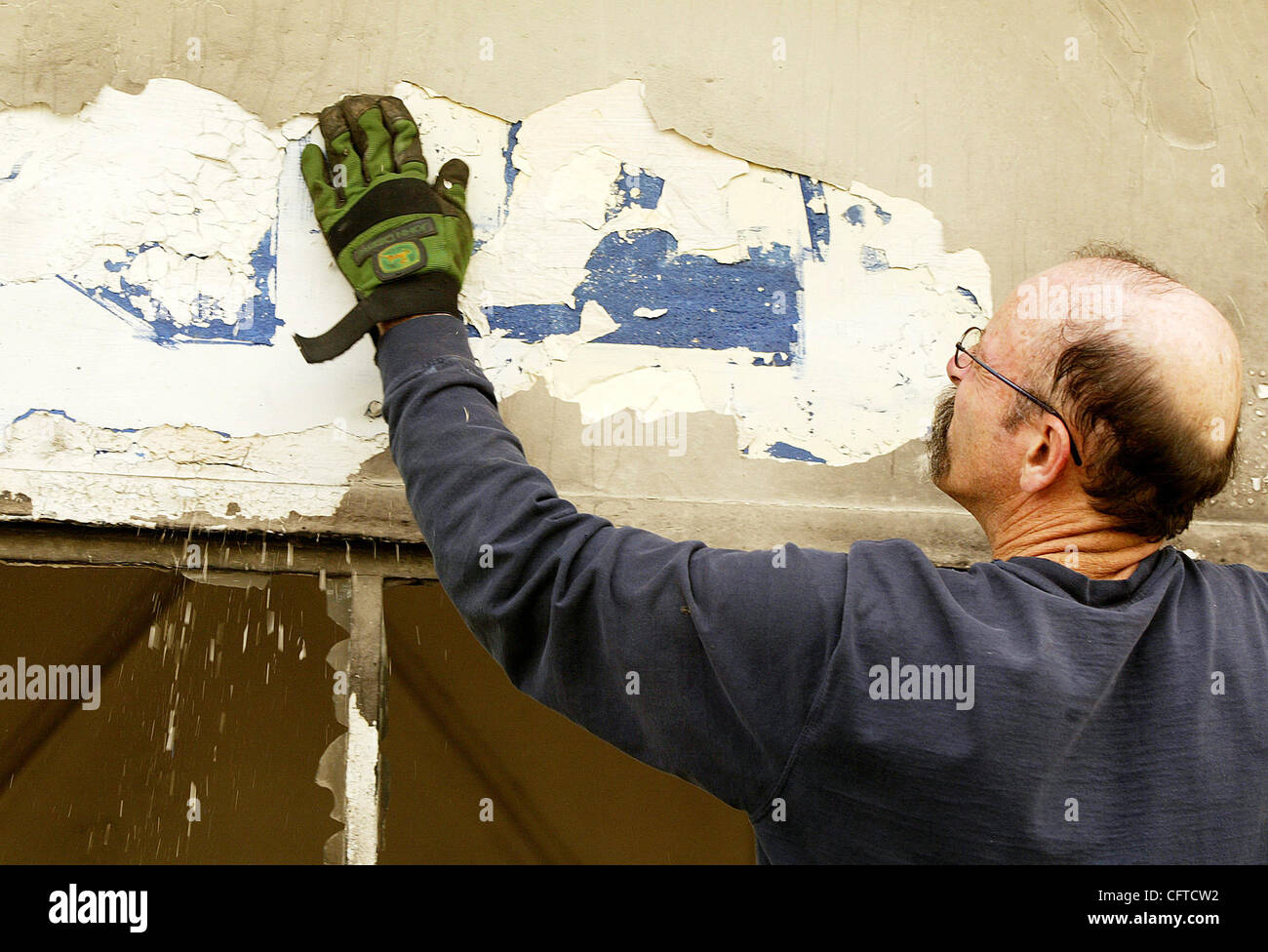 James Perry, a building collector, scrapes layers of paint from the ...