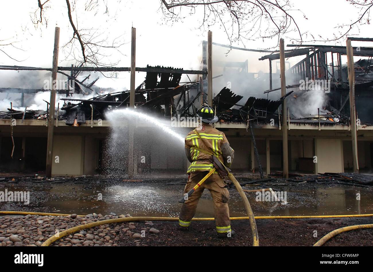 A firefighter works on extinguishing a three-alarm structure fire at ...