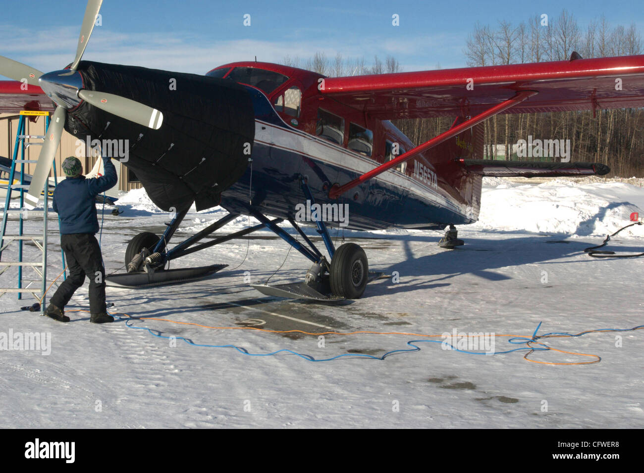 The pilot plugs in the engine of the Talkeetna Air Taxi to warm up ...
