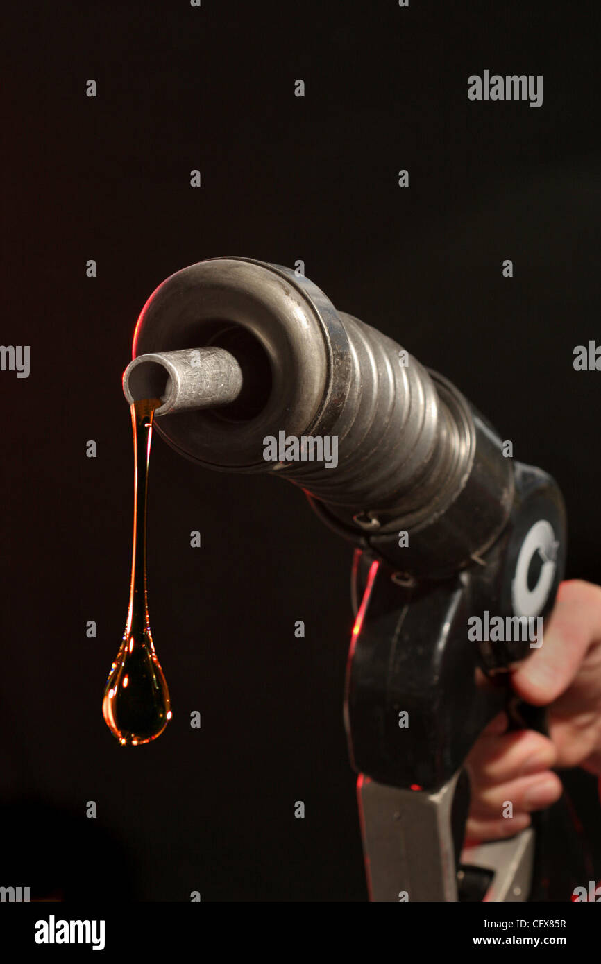 A drop of gas drips from the end of a pump nozzle in this photo ...