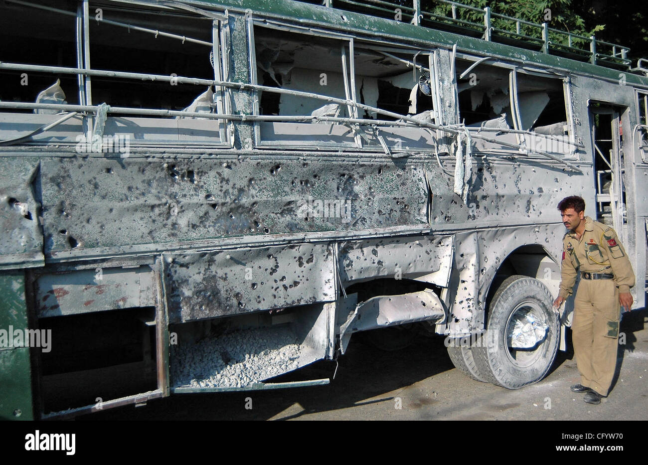 An Indian policeman looks at the damaged army bus after a landmine ...