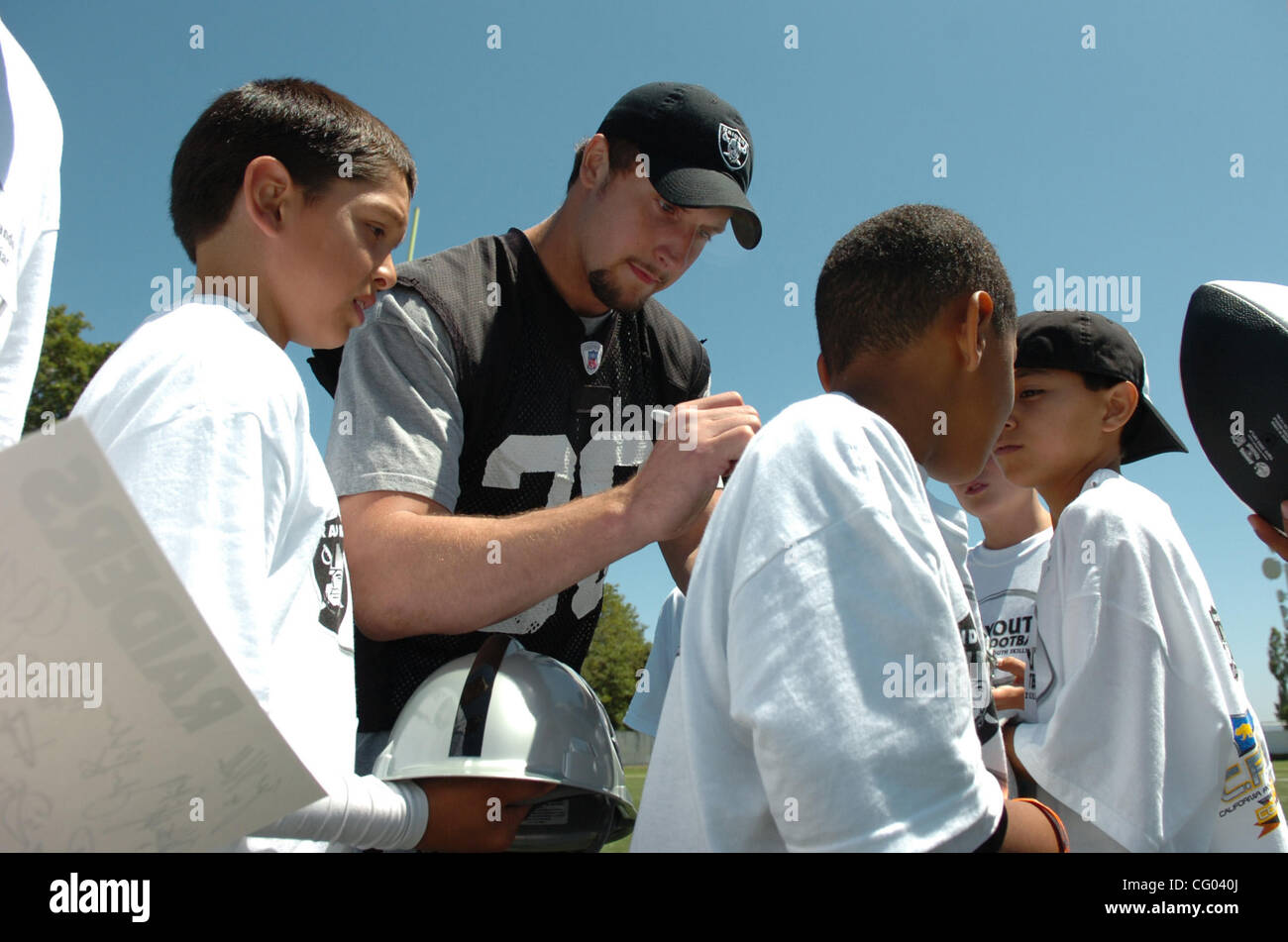 Oakland Raiders Stuart Schweigert signs autographs during a youth ...