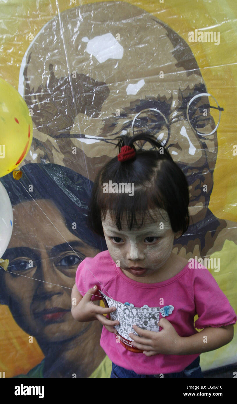 A little child stands next to a portrait of Myanmar opposition leader ...