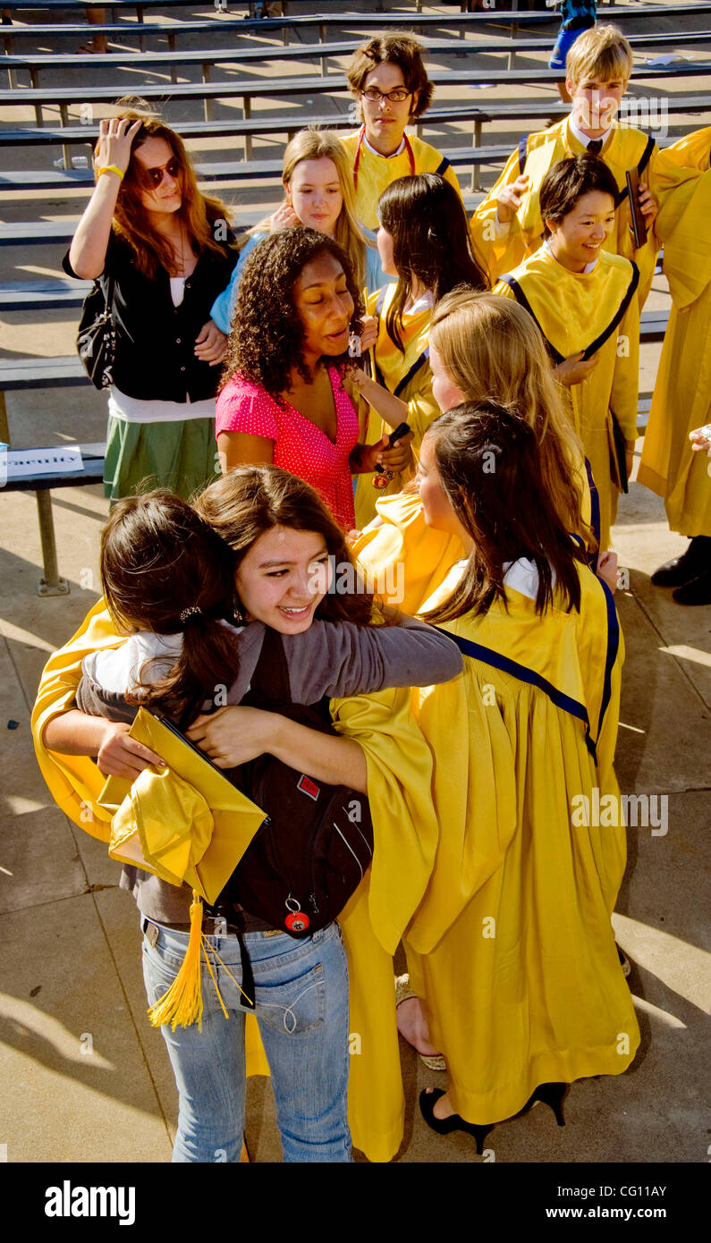 Happy graduating high school seniors in traditional gowns share hugs ...