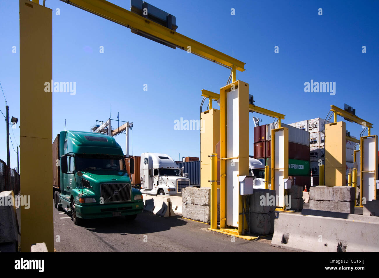 Trucks carrying maritime cargo containers prepare to pass between ...