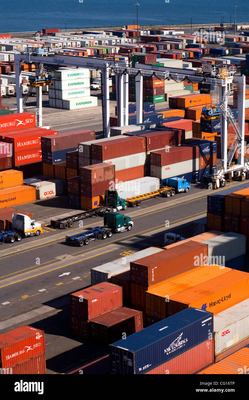 Specialized trucks and overhead cranes shift maritime cargo containers ...
