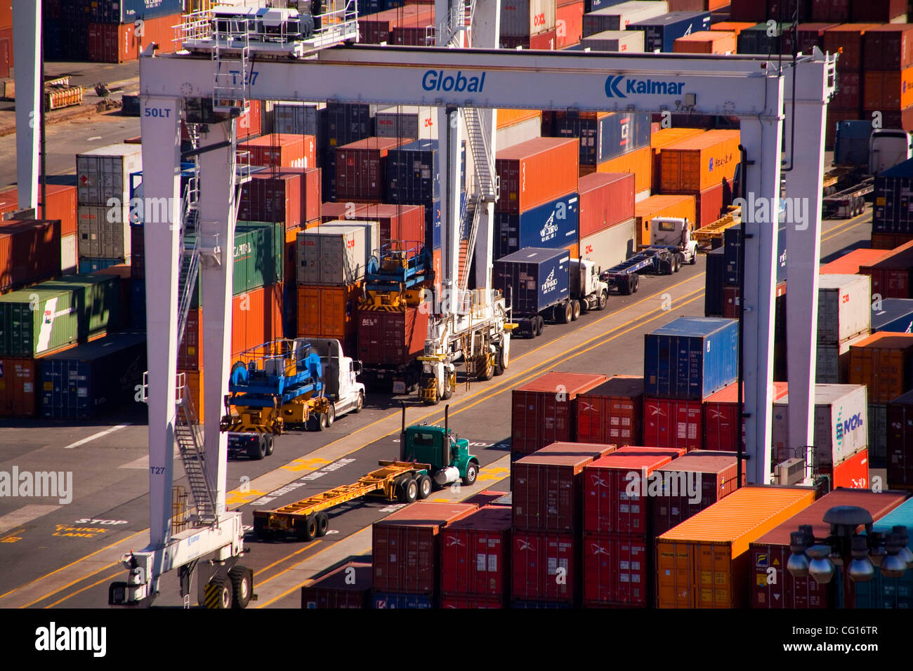 Specialized trucks and overhead cranes shift maritime cargo containers ...