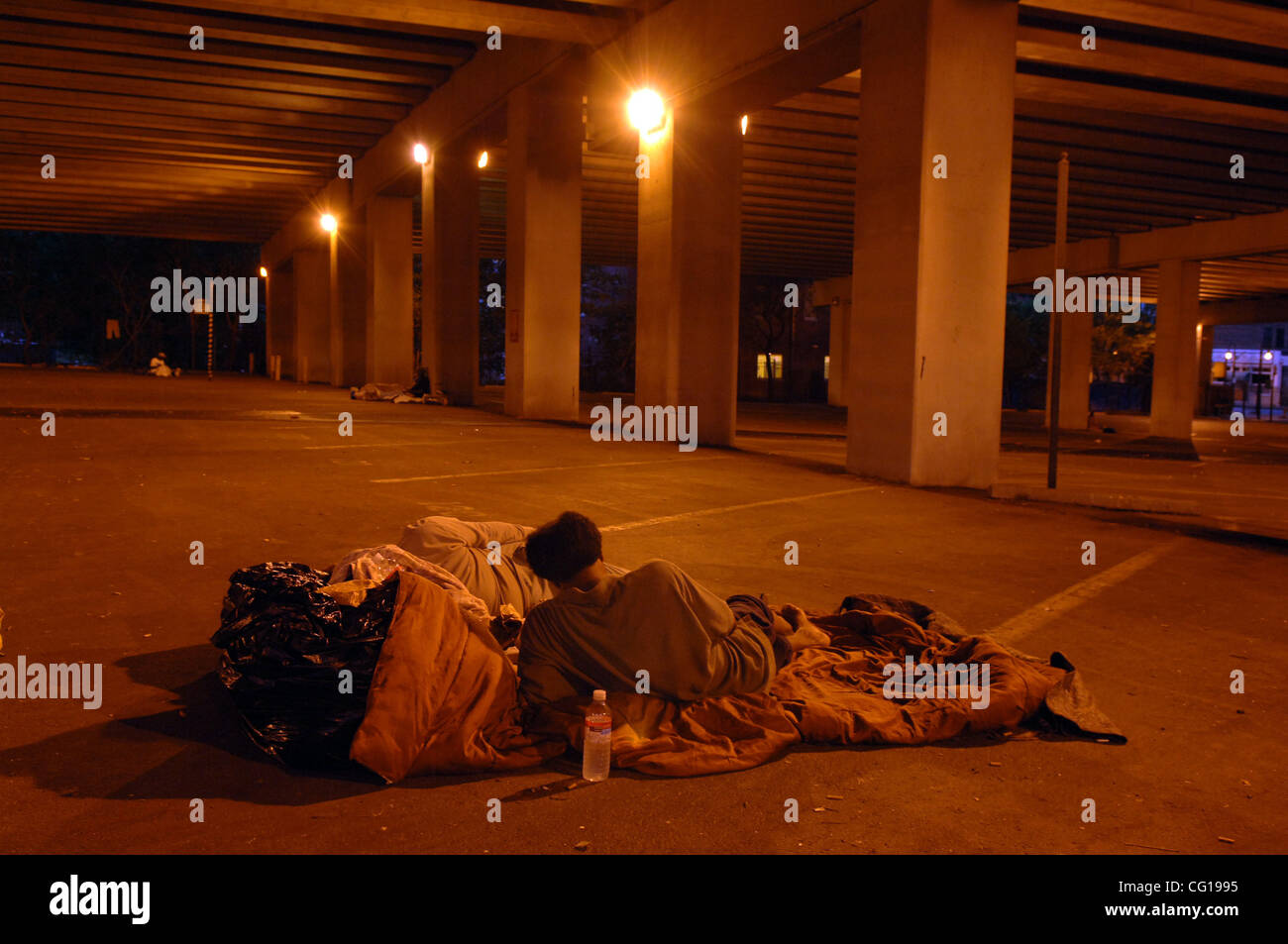 Homeless couples settle in for the night in an empty car park ...
