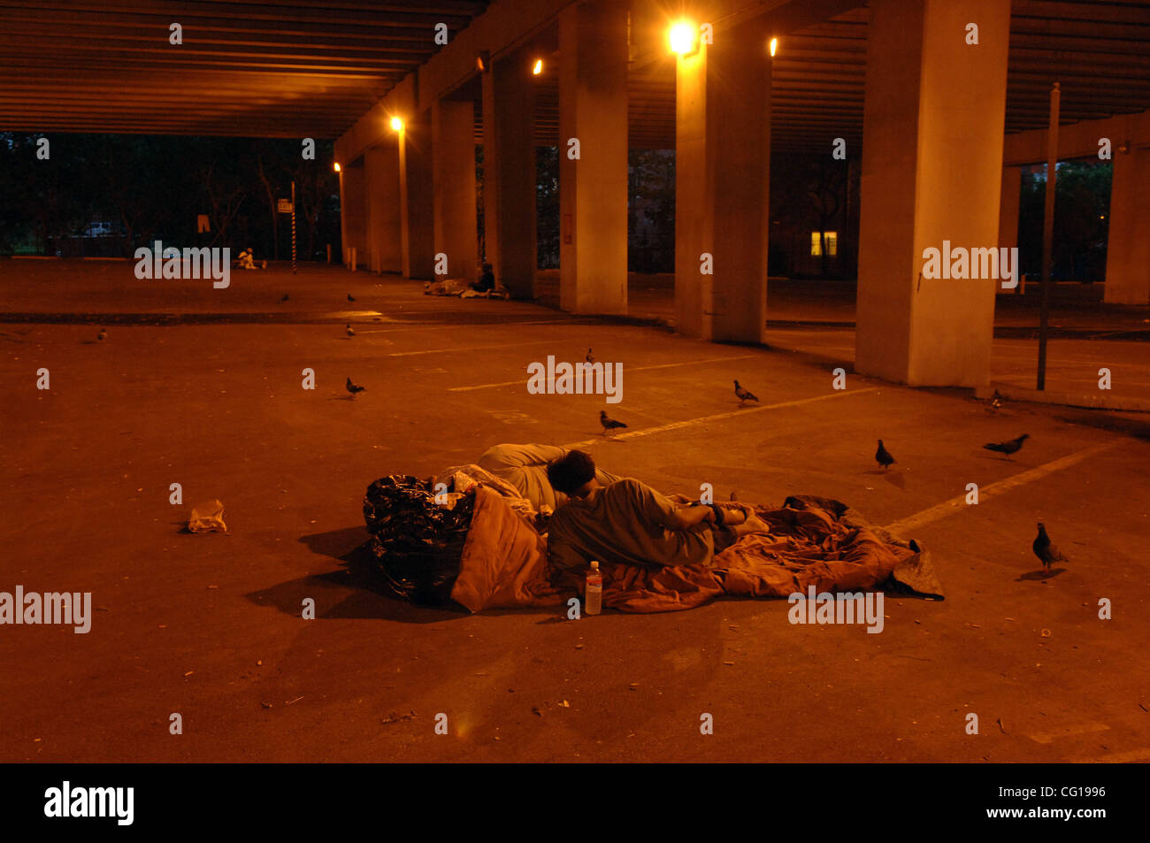 Homeless couples settle in for the night in an empty car park ...