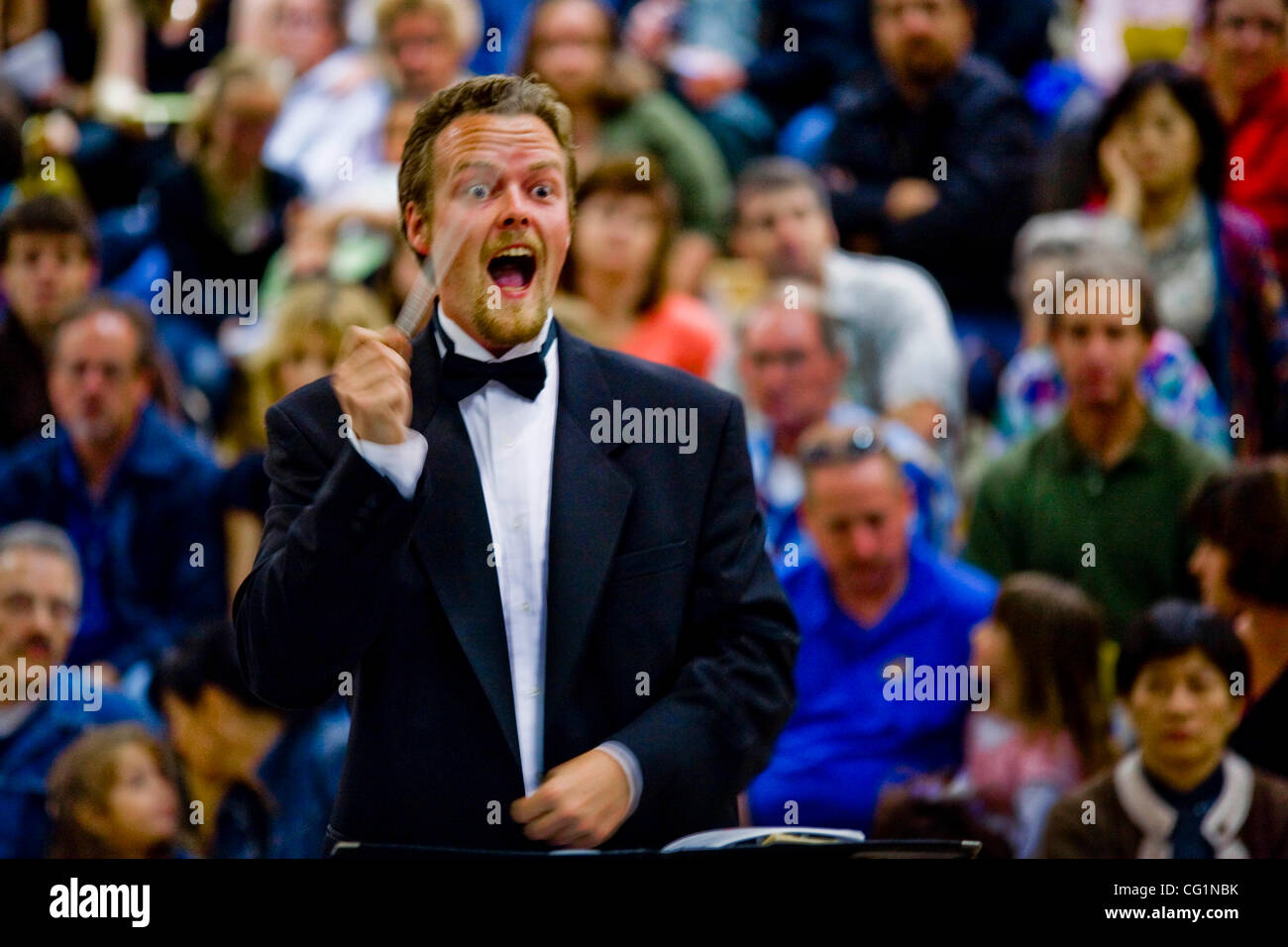 The conductor of a student band directs his musicians at a concert in a ...