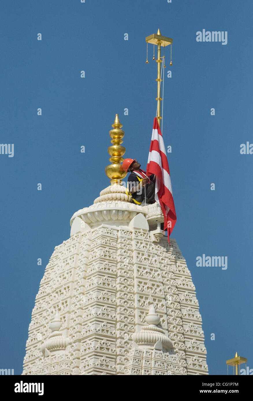 A man places a flag atop a spire during dedication ceremonies of the ...