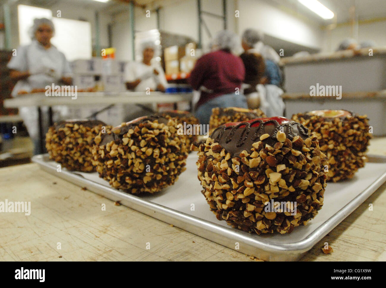 Fuji apples wrapped in carmel, dunked in chocolate and almonds sit on a ...