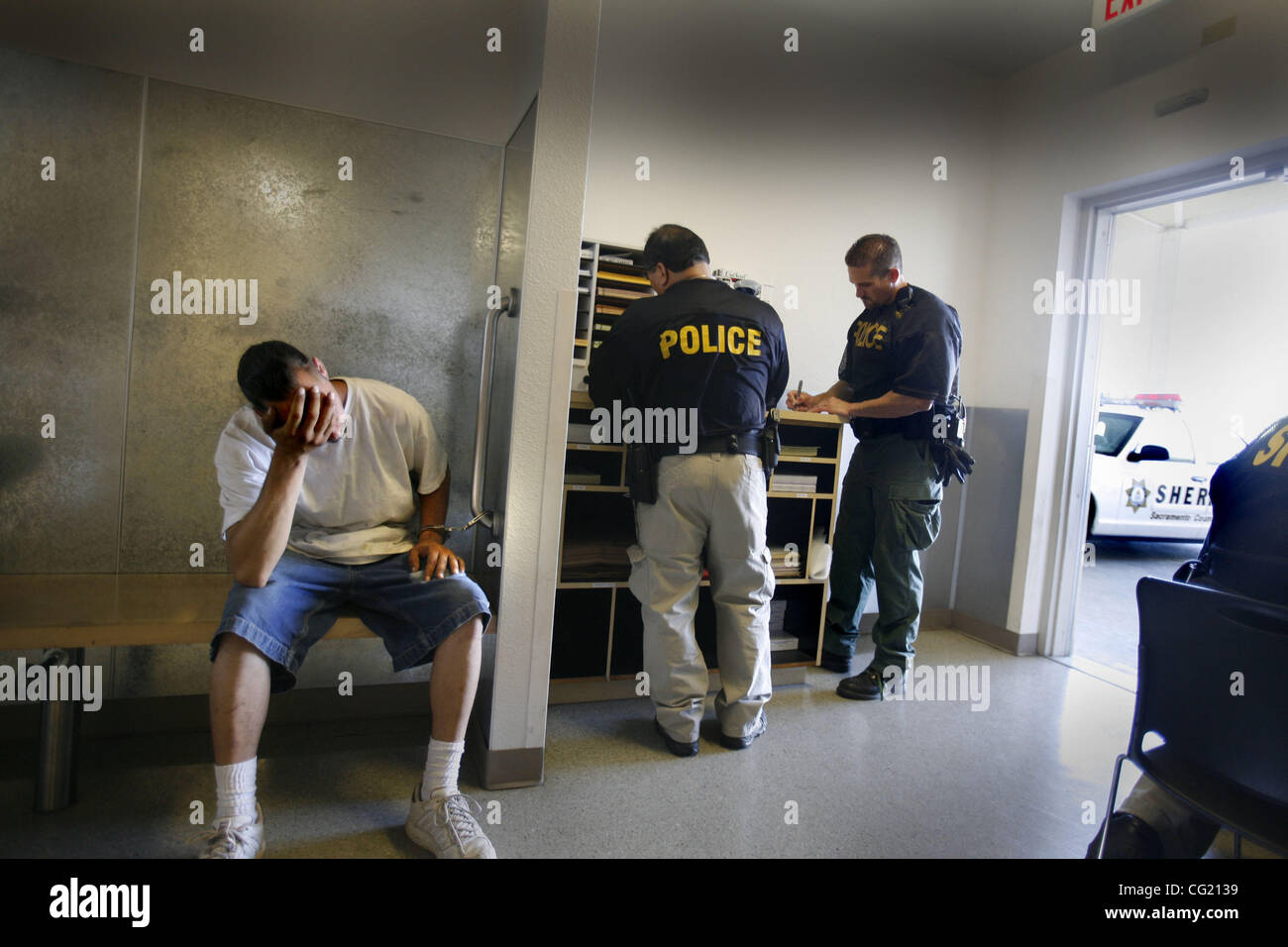 A suspected gang member is locked to a bar as he is processed in the ...