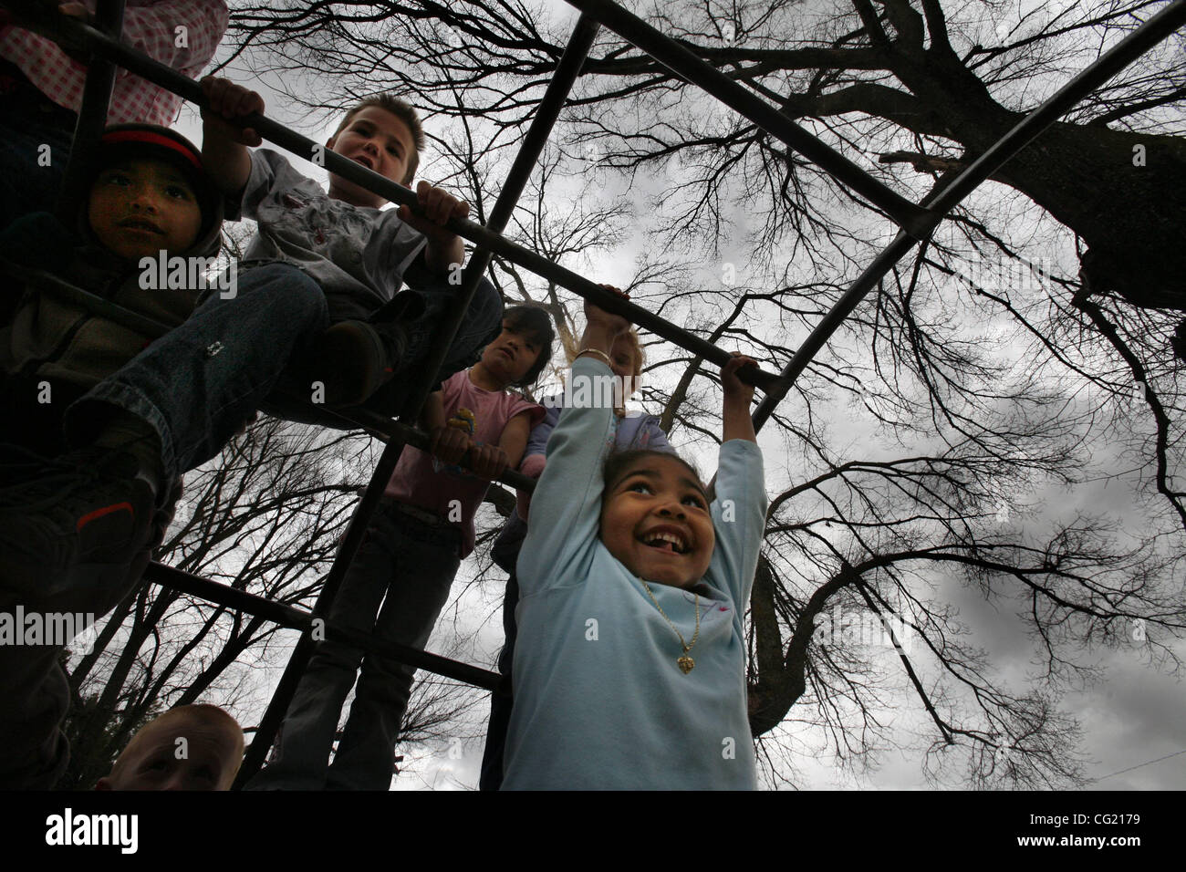 Kindergarten students play during recess under large trees that ...