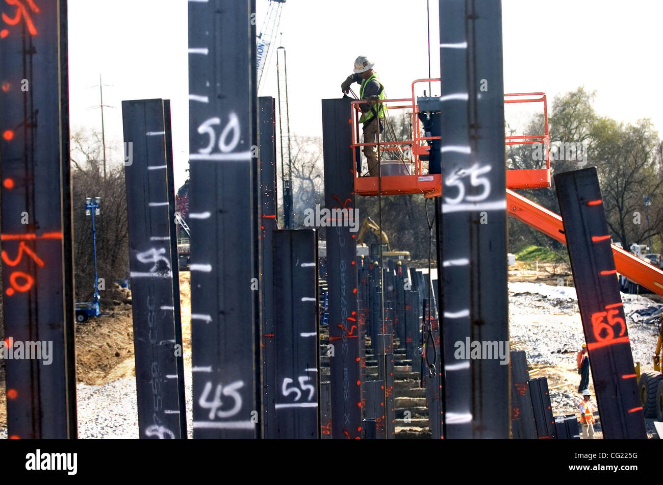 Pile Driver Dave Stephens attaches a crane cable to steel pilings ...