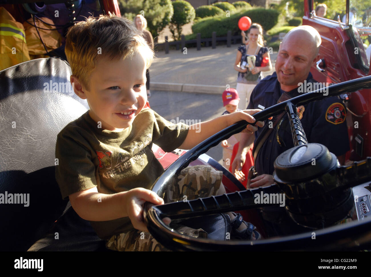 Logan combs (cq, left), 3, takes the driver seat of a fire truck under ...
