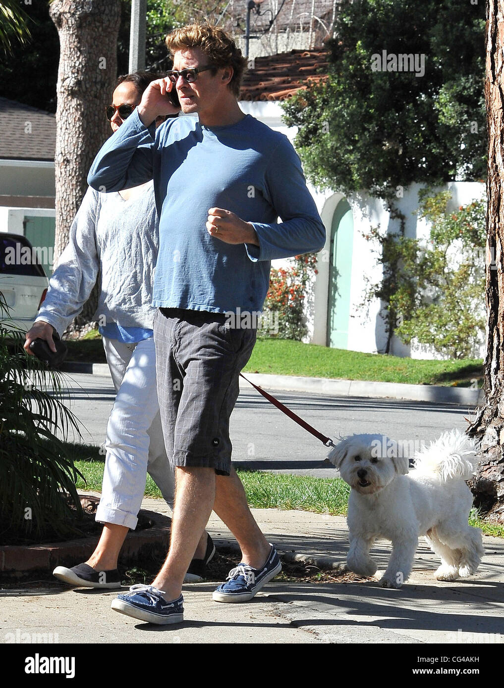 Simon Baker talking on his cellphone with his wife Rebecca Rigg walking ...