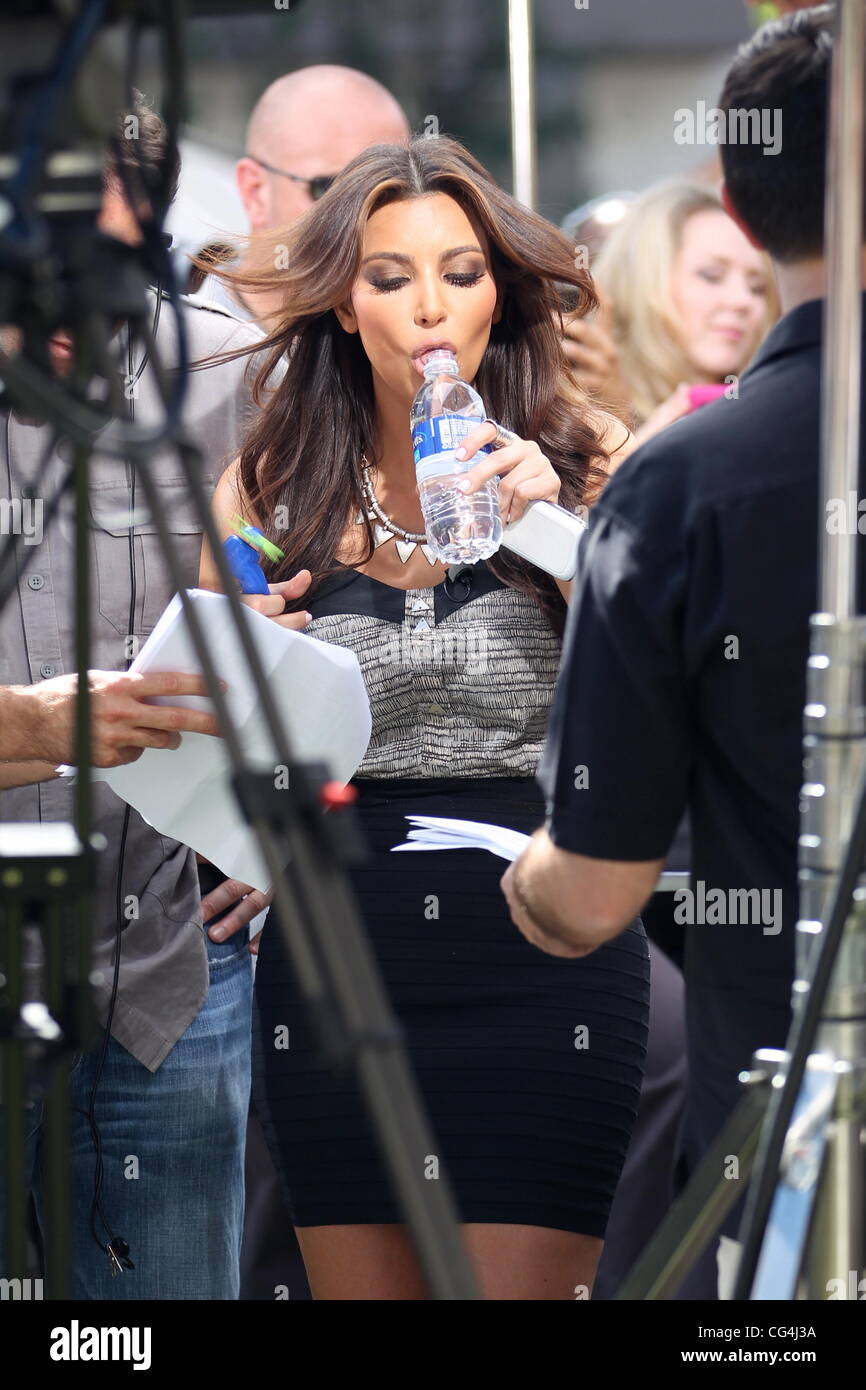 Kim Kardashian using a fan and drinking water while filming an ...