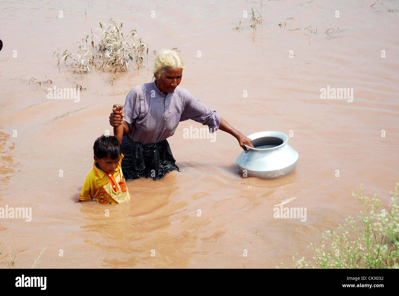 Flood affected woman with her child pass through flood water at a flood ...