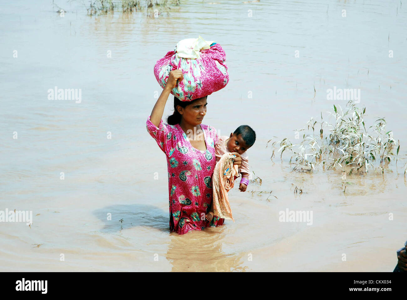 Flood affected woman with her child pass through flood water at a flood ...