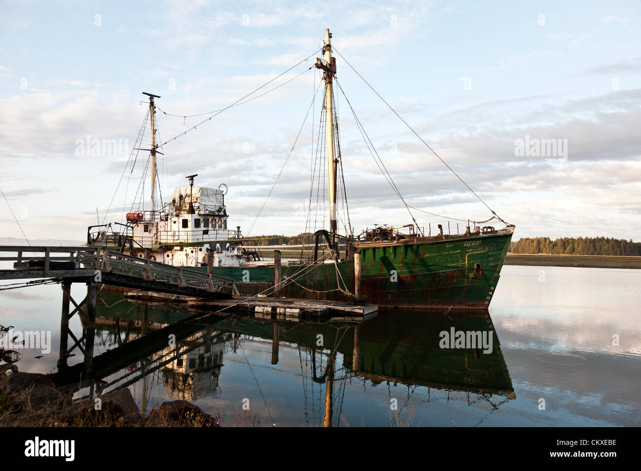 old fishing trawler named Hero with rusting green hull reflected in ...