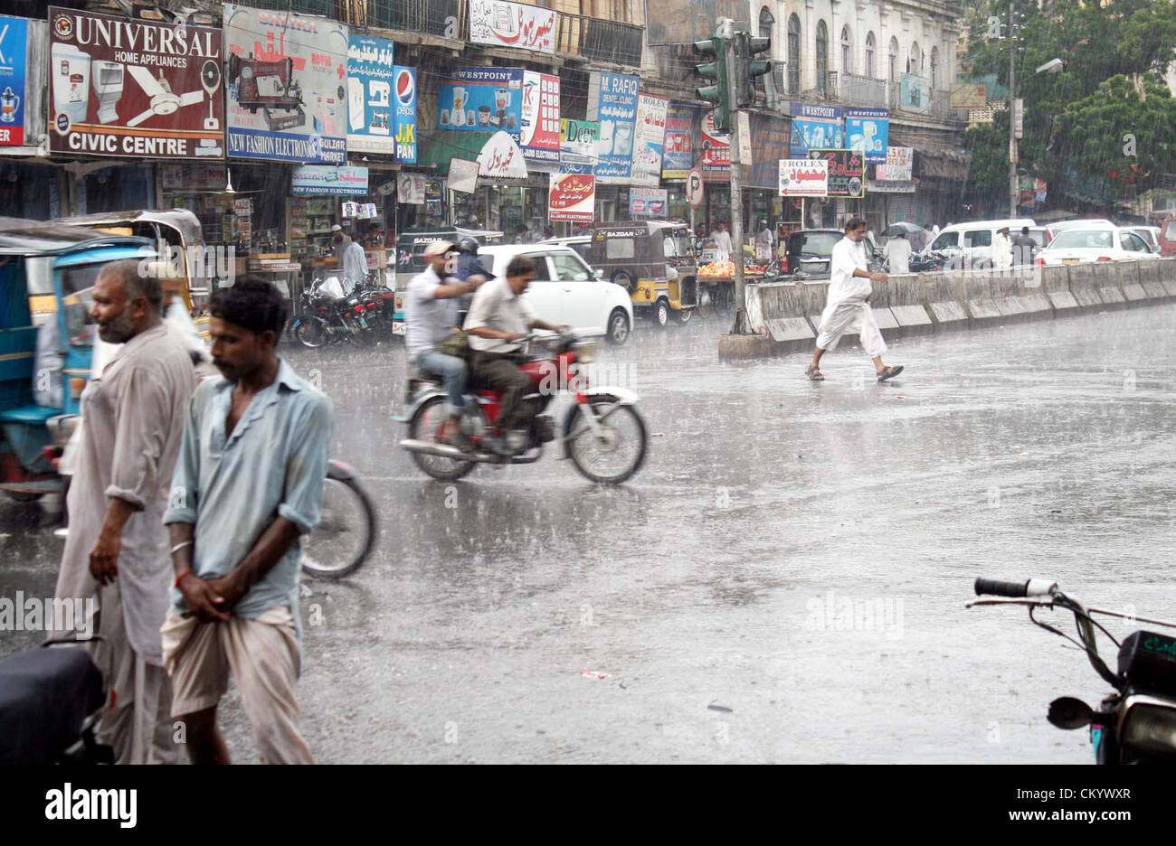 Commuters pass through rain water that was stand at road during heavy ...