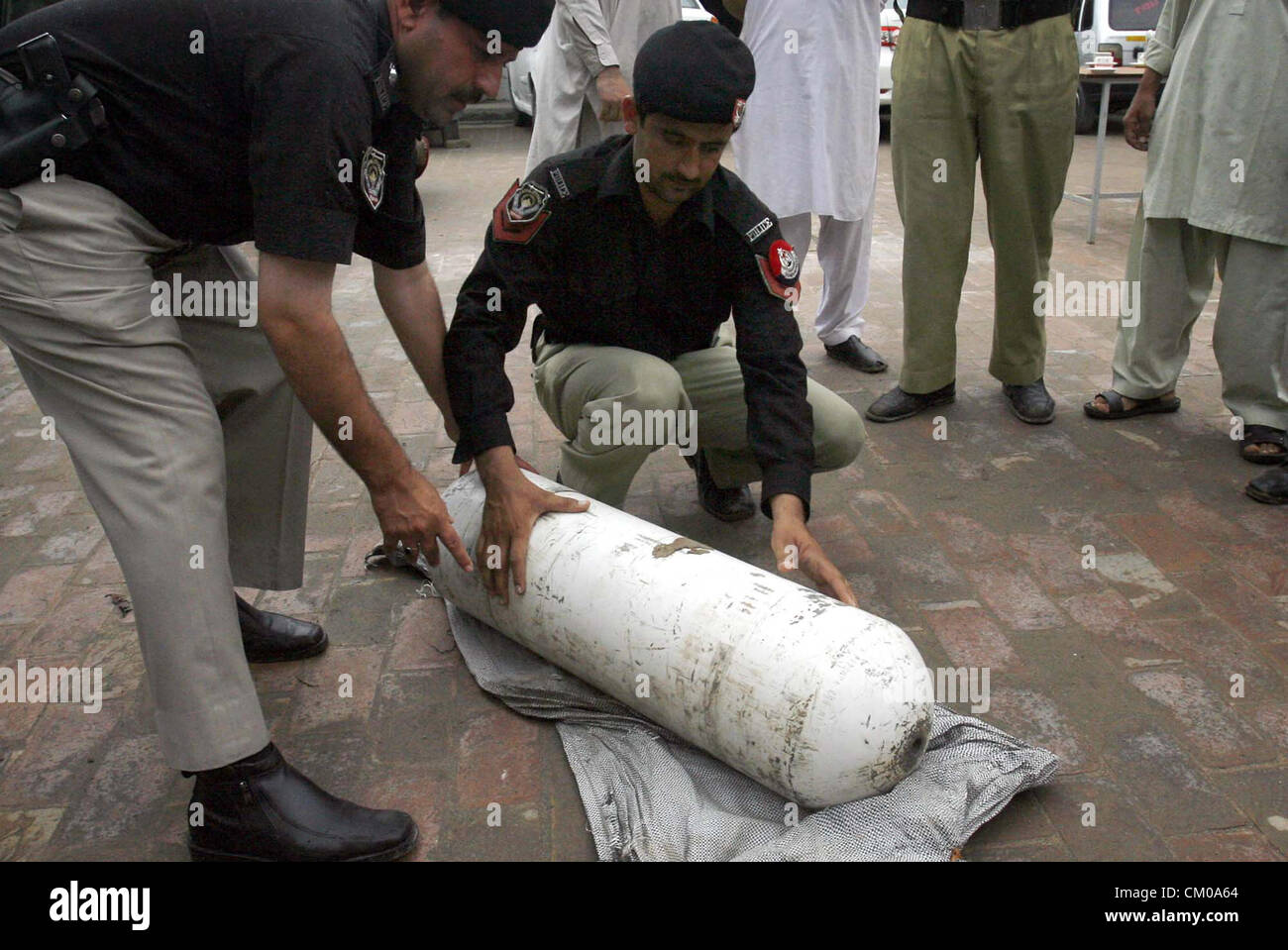 Policemen look the explosive material tank which was recovered from a ...