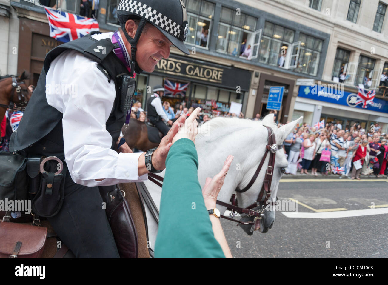 A mounted police officer gives a member of the public a high five at ...